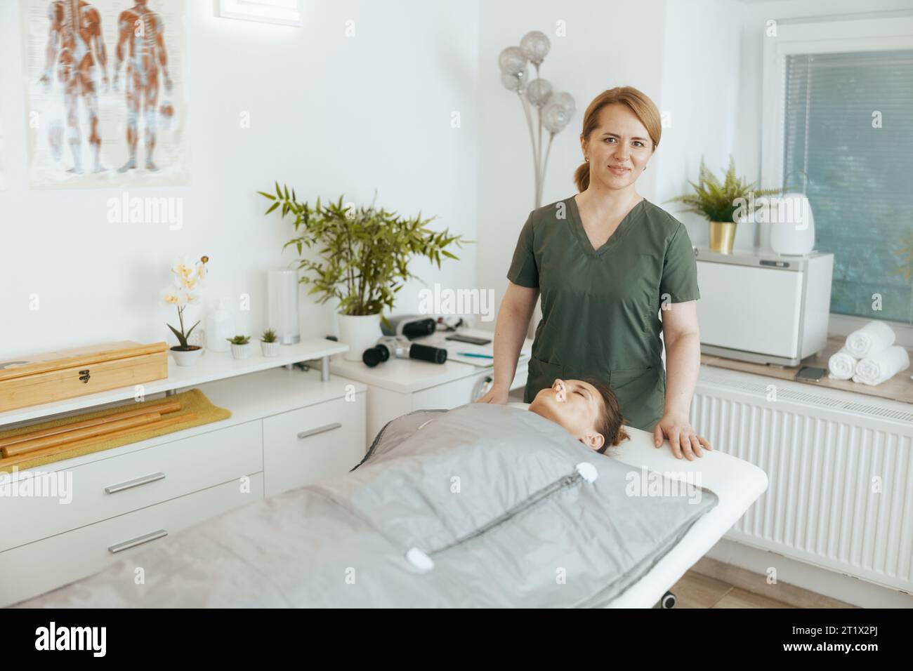 Healthcare time. happy female medical massage therapist in massage cabinet with client doing ...