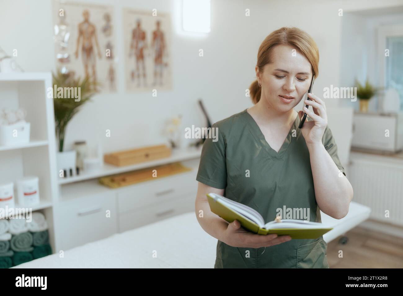 Healthcare time. concerned female medical massage therapist in massage cabinet with notebook ...