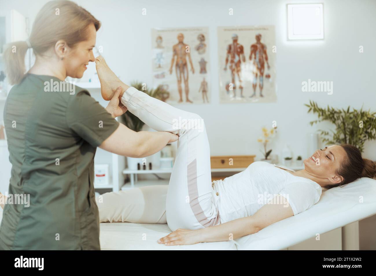 Healthcare time. happy massage therapist woman in massage cabinet with client conducting ...