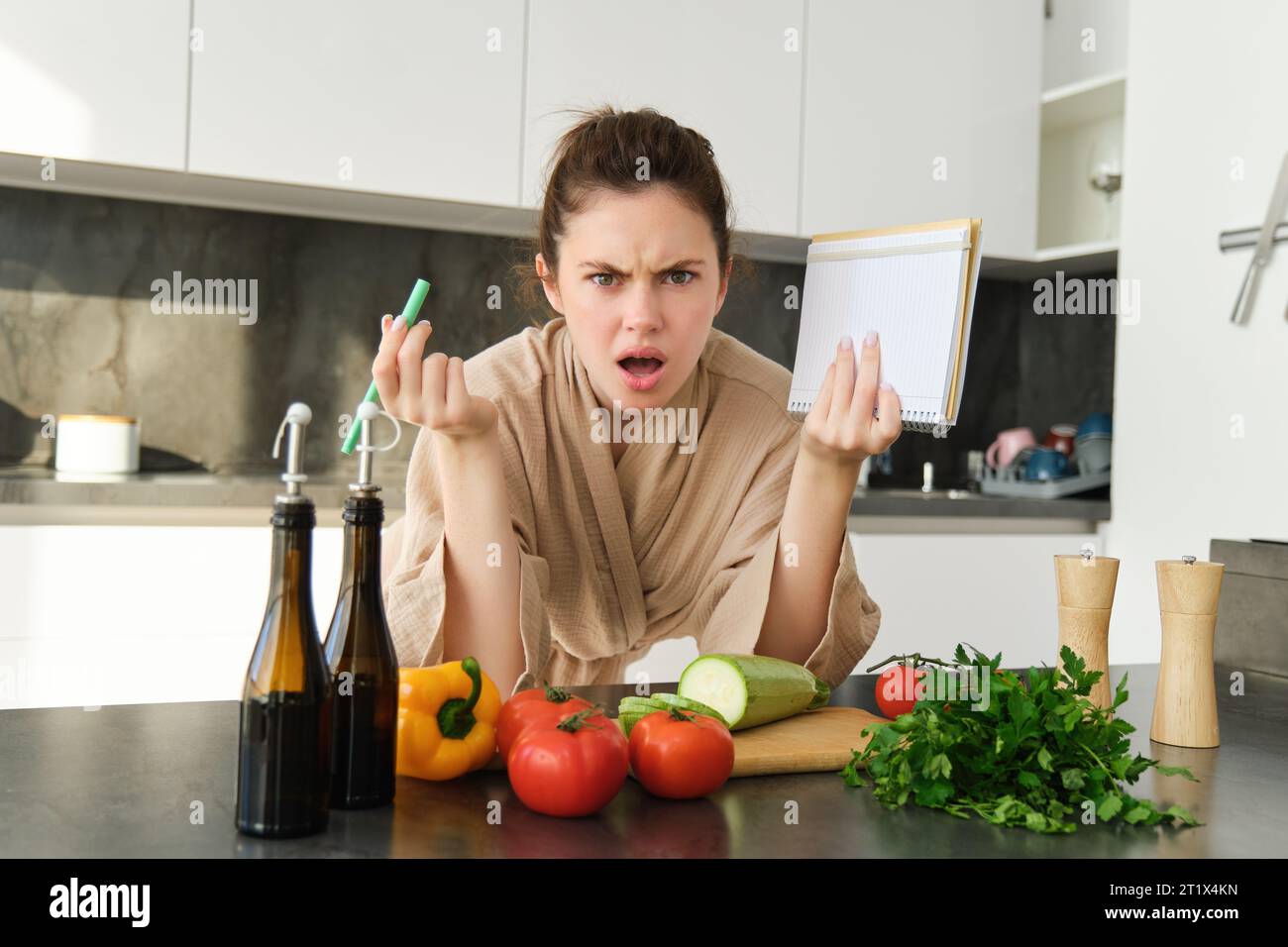 Portrait of woman with angry face, standing near vegetables and looking ...