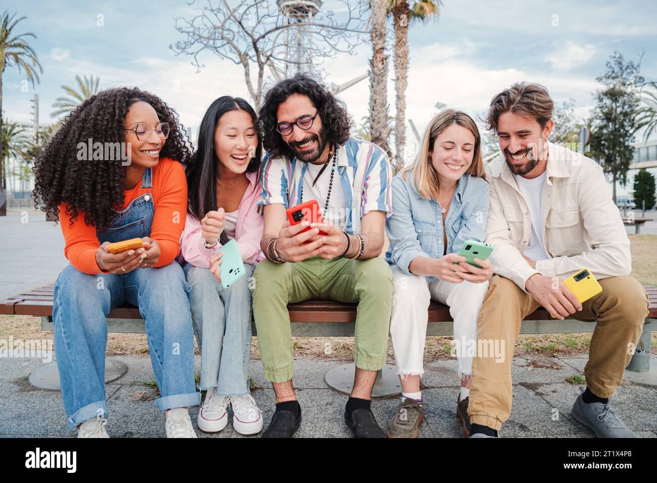 Group of multiracial young adult friends using their cellphones ...