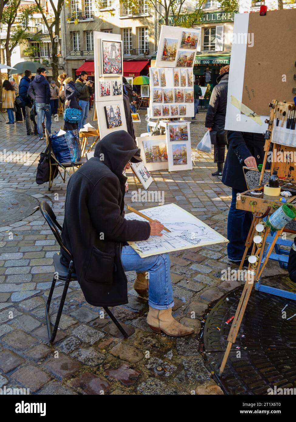 An artist at work drawing while displaying pictures for sale in Place ...