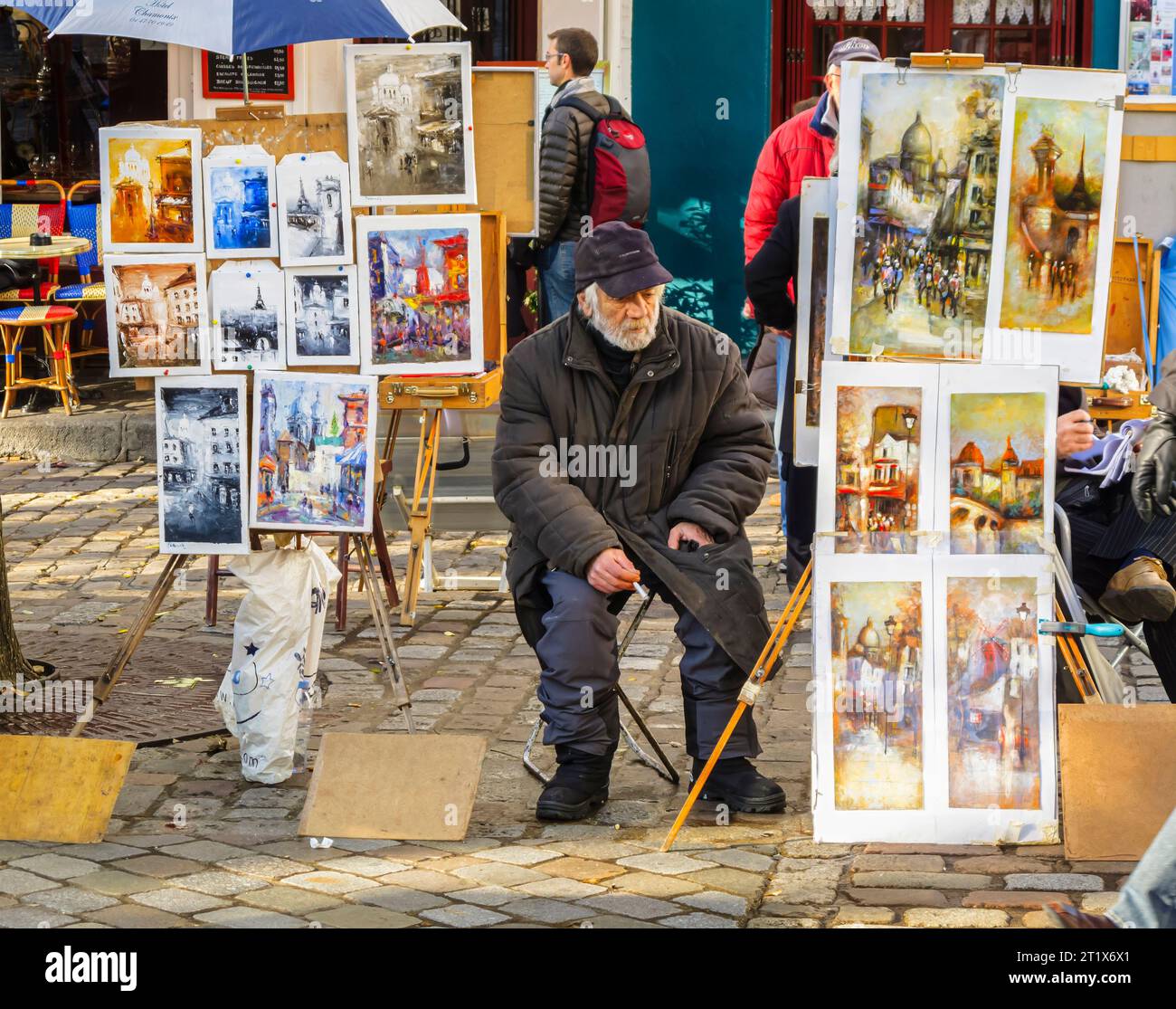 Seller sitting selling works of art, paintings and displaying pictures ...