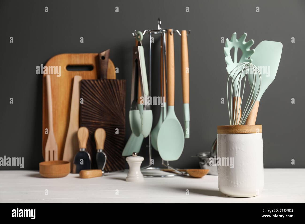 Set of different kitchen utensils on white wooden table against grey ...
