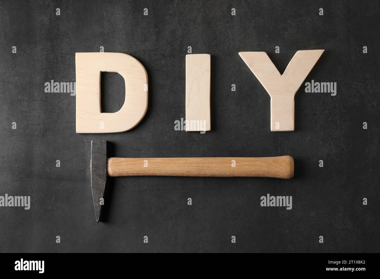 Abbreviation DIY made of wooden letters and hammer on dark background ...