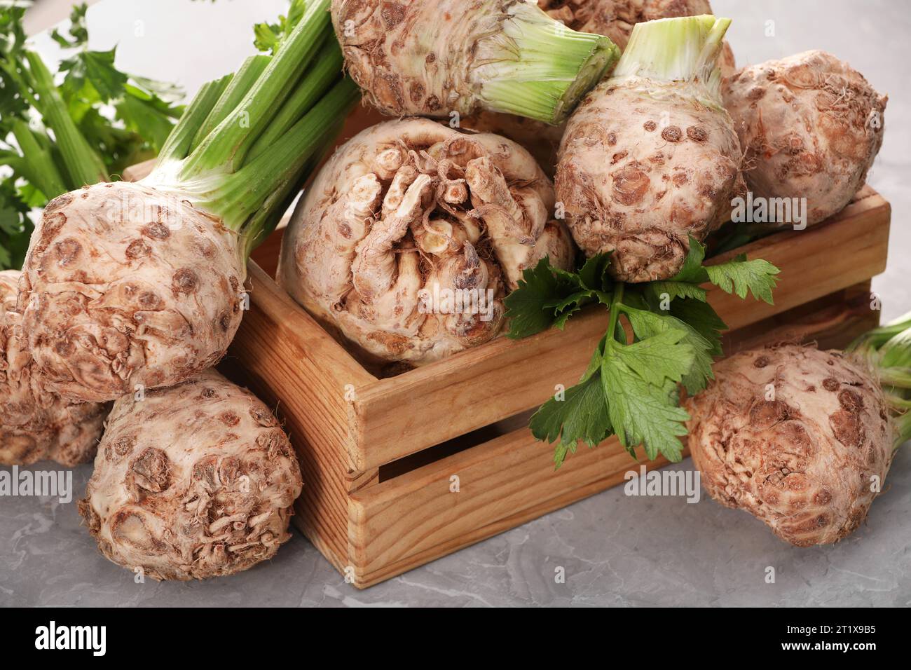 Fresh raw celery roots and wooden crate on light grey table Stock Photo ...