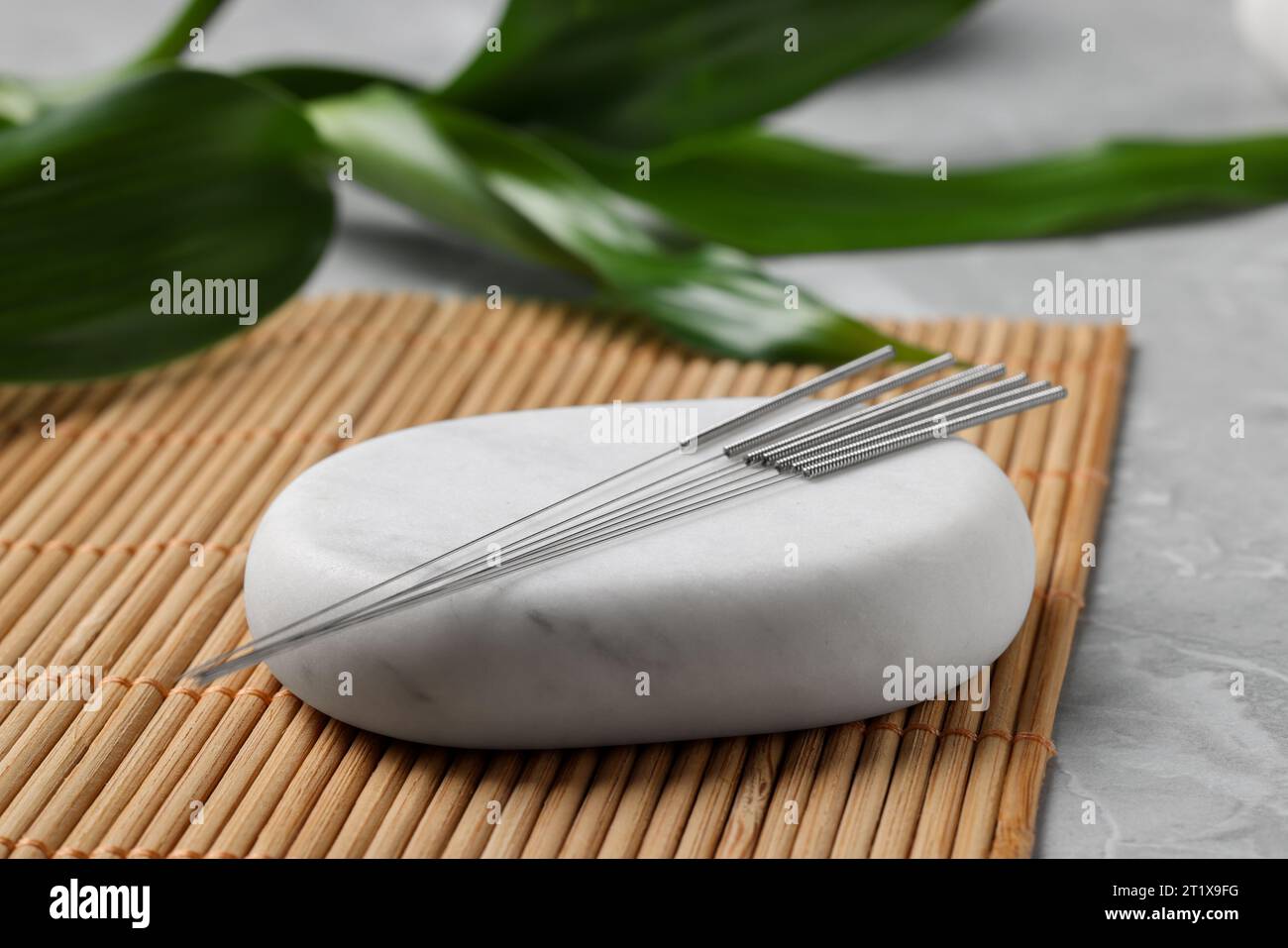 Stone with acupuncture needles on light grey marble table Stock Photo ...