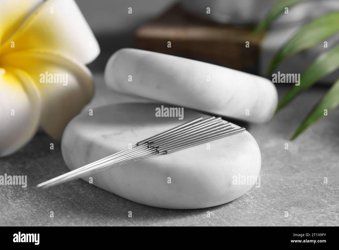 Stones with acupuncture needles and lily flower on grey table, closeup ...