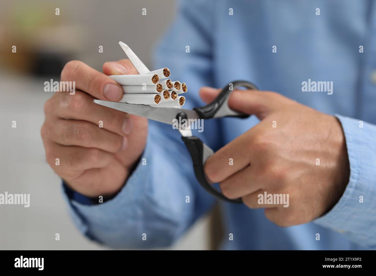 Stop smoking concept. Man cutting cigarettes on blurred background ...