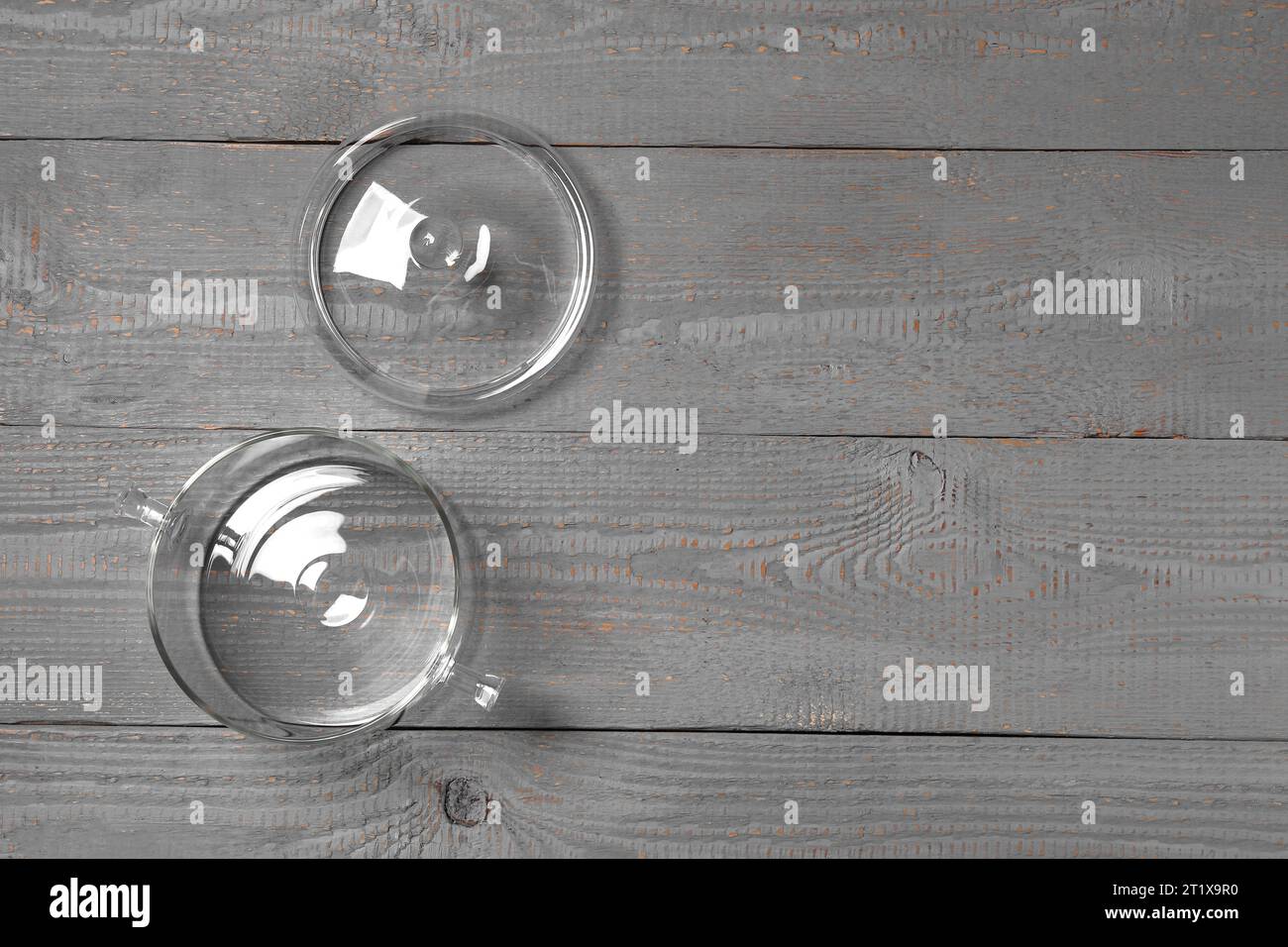 Empty glass pot and lid on grey wooden table, flat lay. Space for text ...
