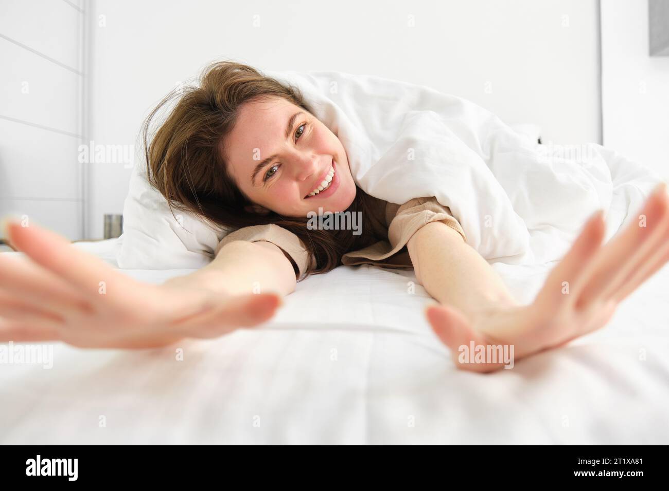 Gorgeous girl laughing and smiling, stretching in hotel bed, enjoying ...