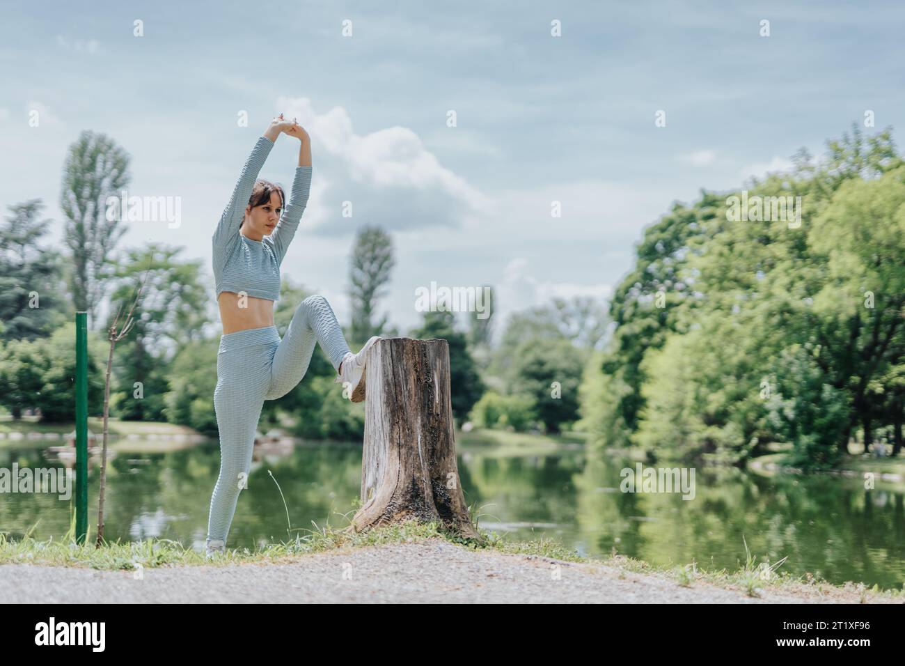Fit girls perform cardio and stretching exercises in a city park ...