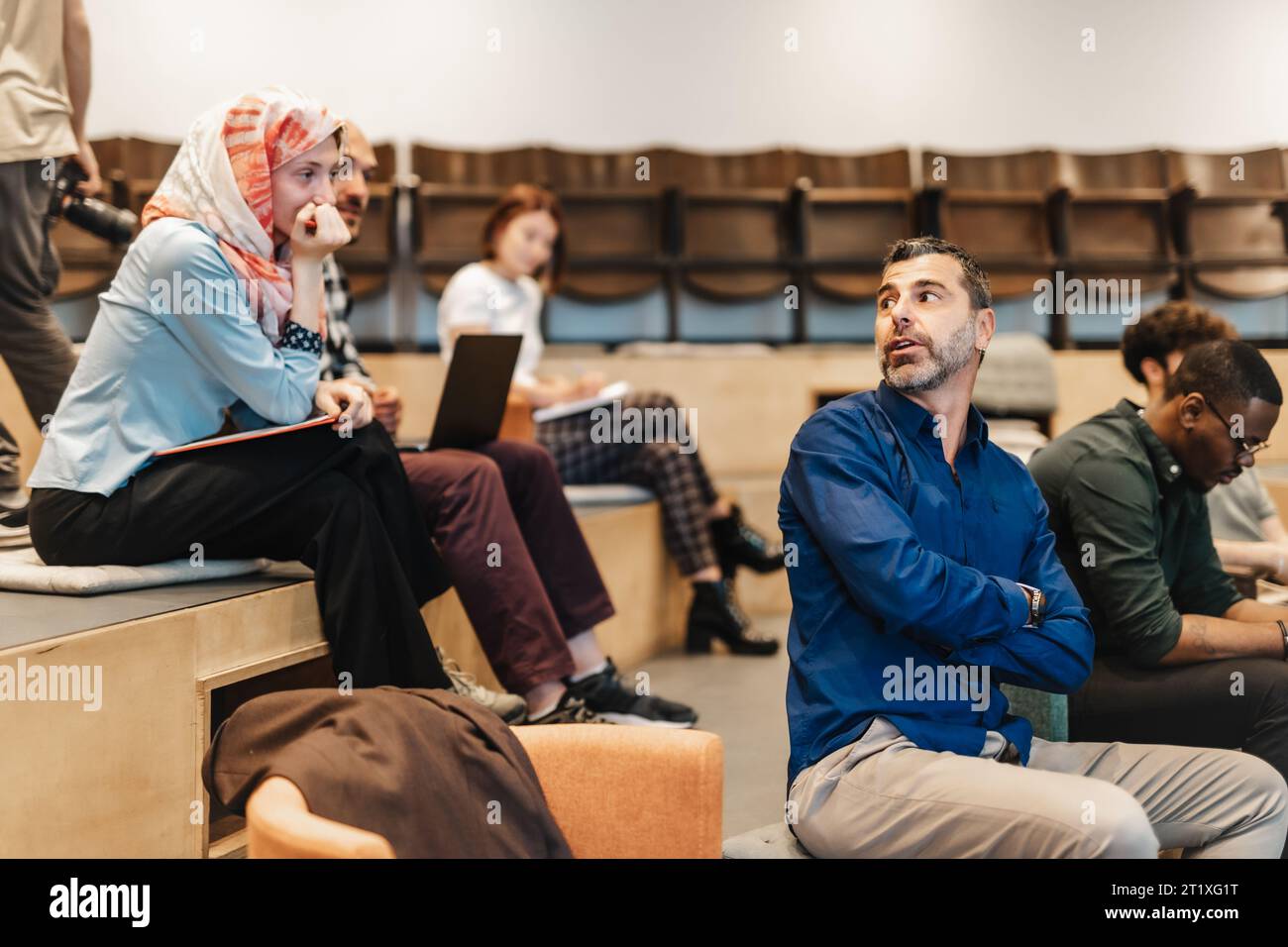 Multicultural business team gathered at small amphitheater discussing ...