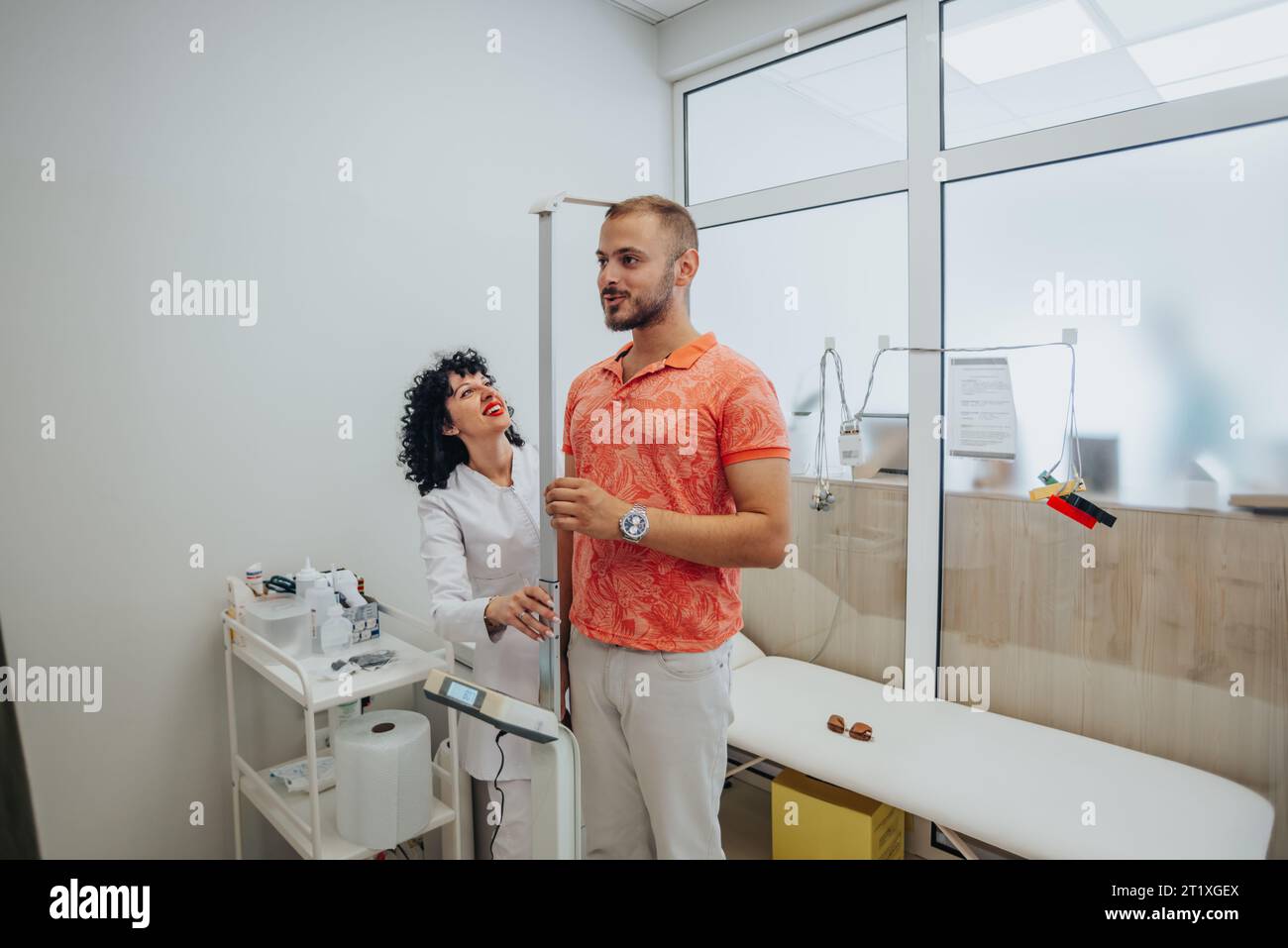 Female doctor measuring young patient height using metric scale at the ...