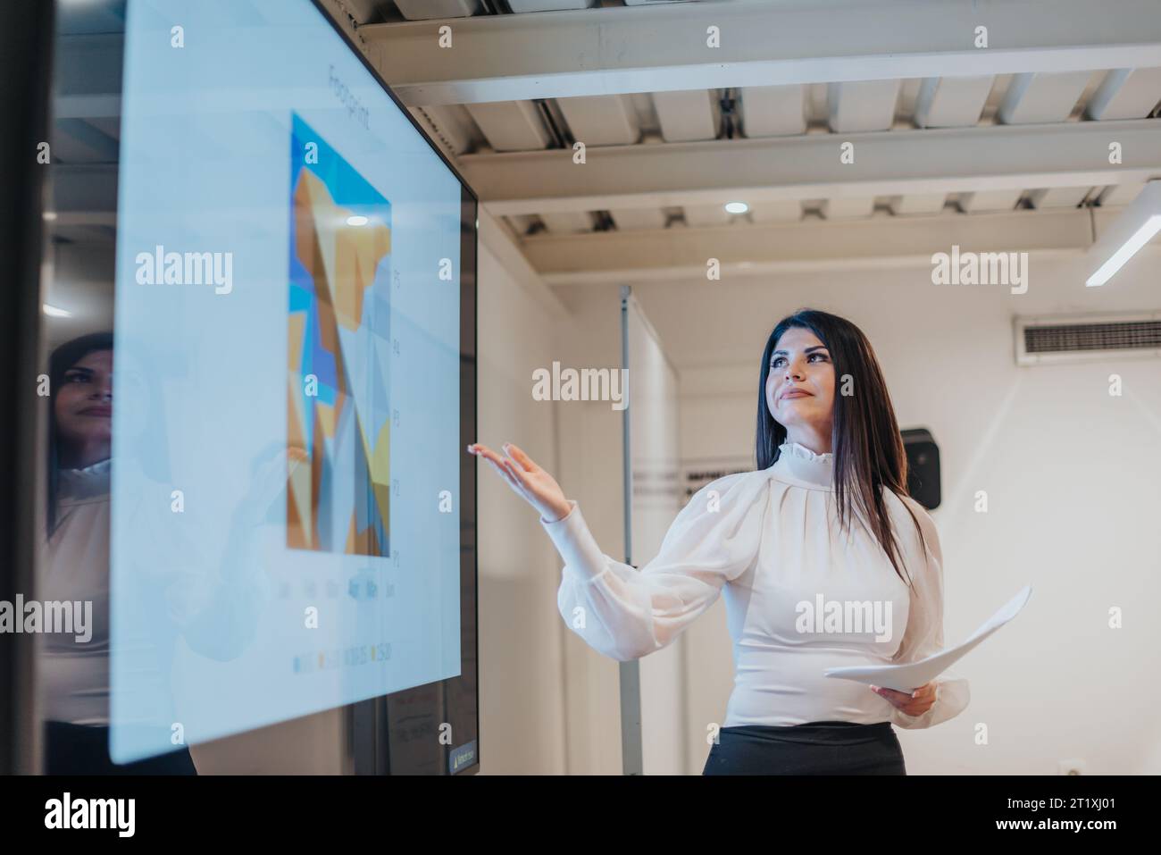 Female businesswoman presenting on a TV set in front of her colleagues ...