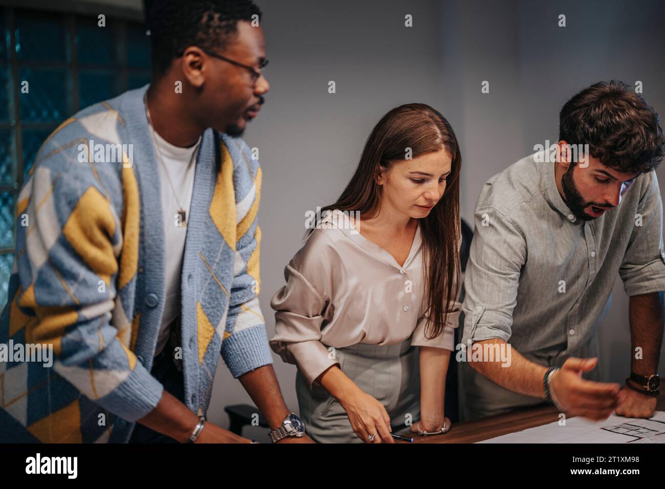 Multiracial executives discuss blueprints in a collaborative boardroom ...