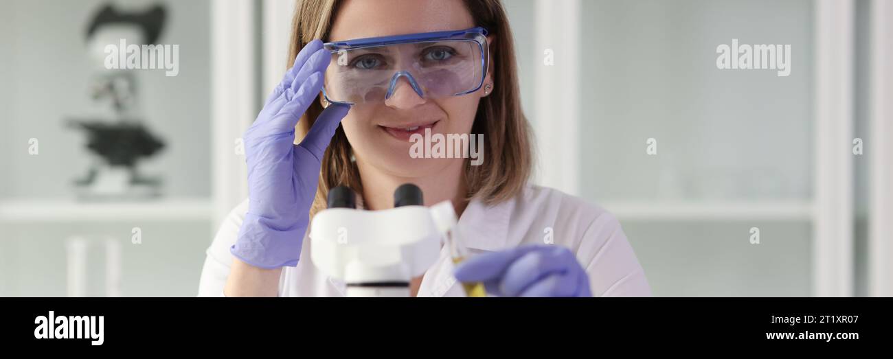 Positive woman adjusts goggles before examining sample Stock Photo - Alamy