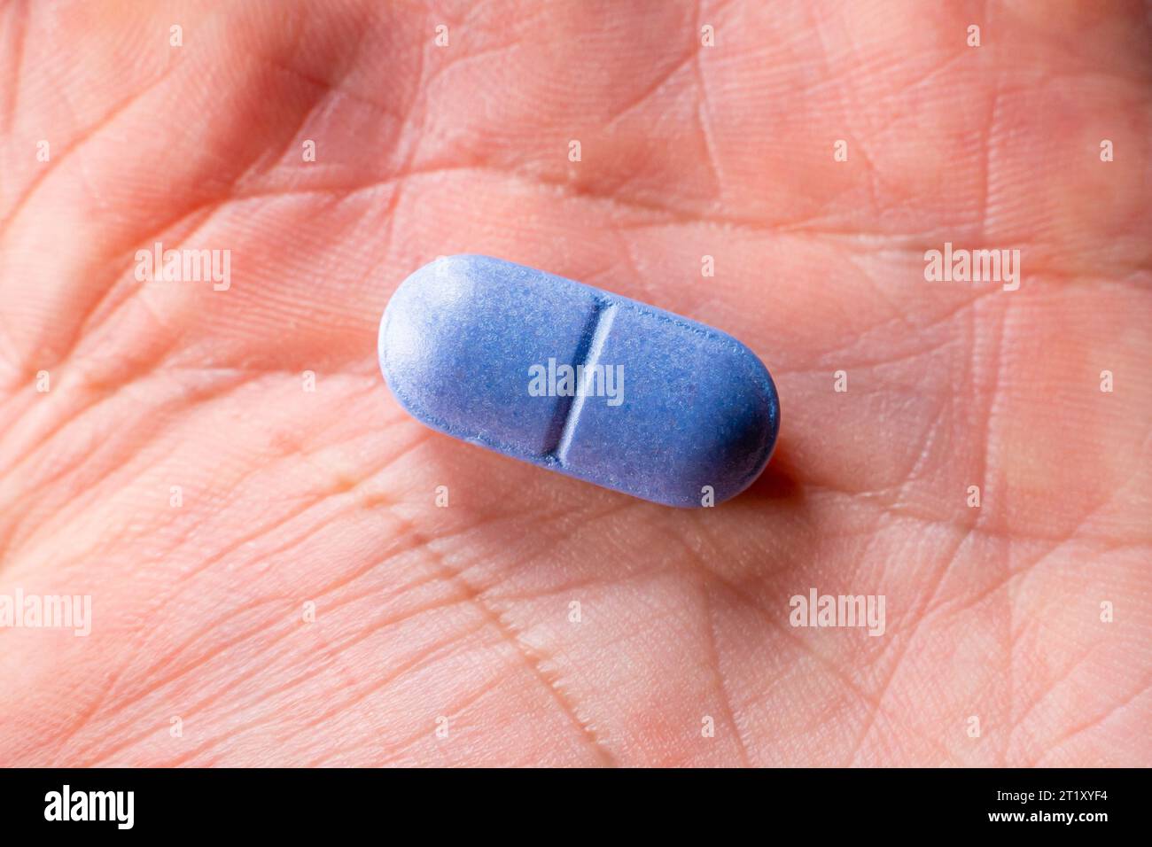 The blue pill lies in the center of the palm, close-up. Oblong blue ...