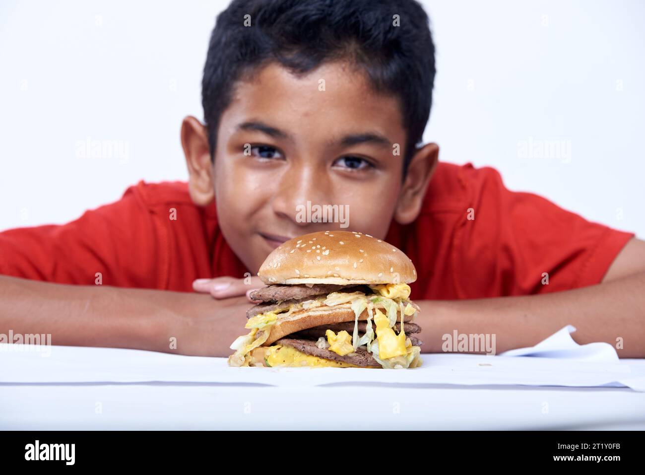 Happy boy eating a hamburger and smiling at the camera on white ...