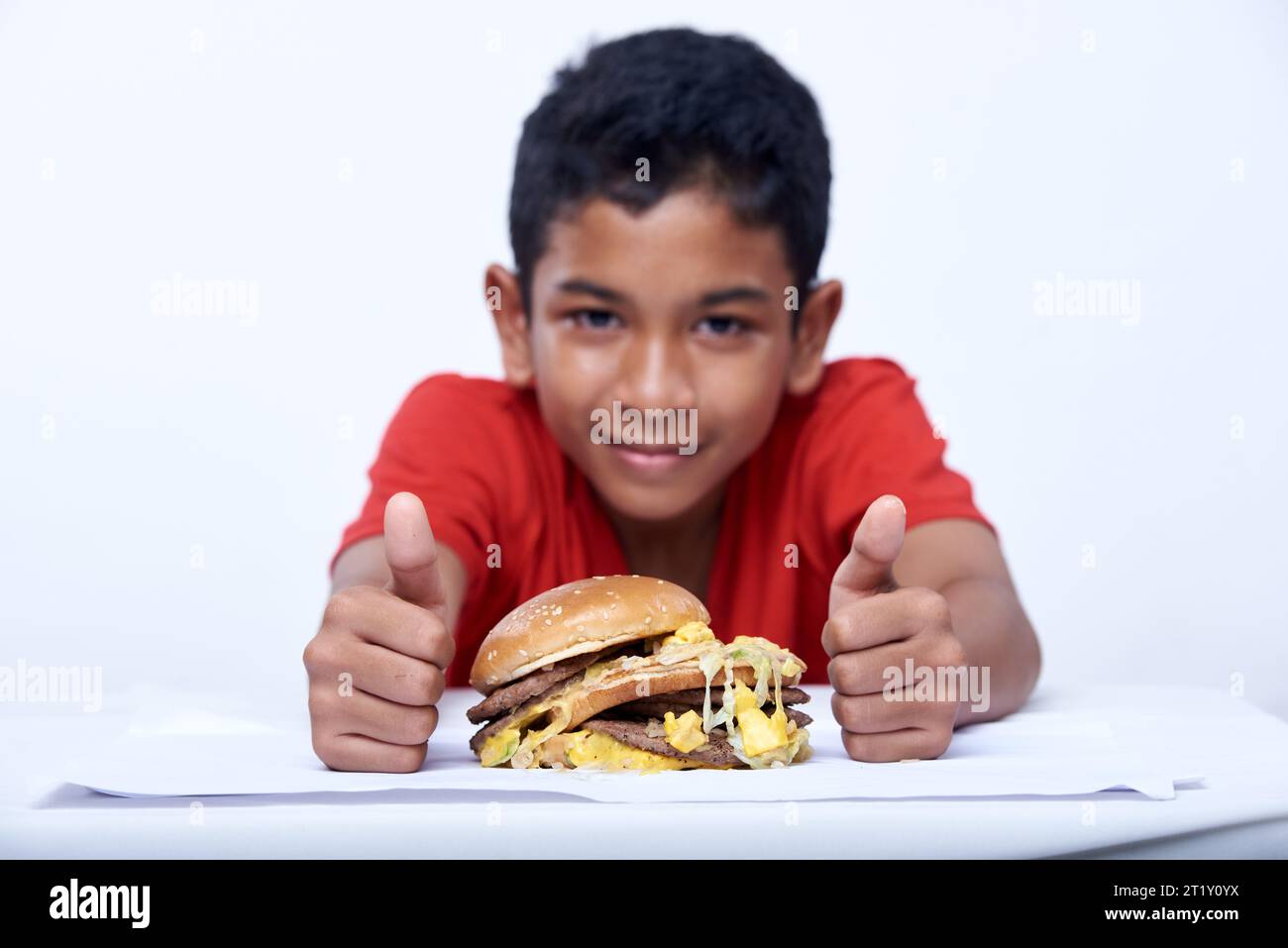 Happy boy eating a hamburger and smiling at the camera on white ...
