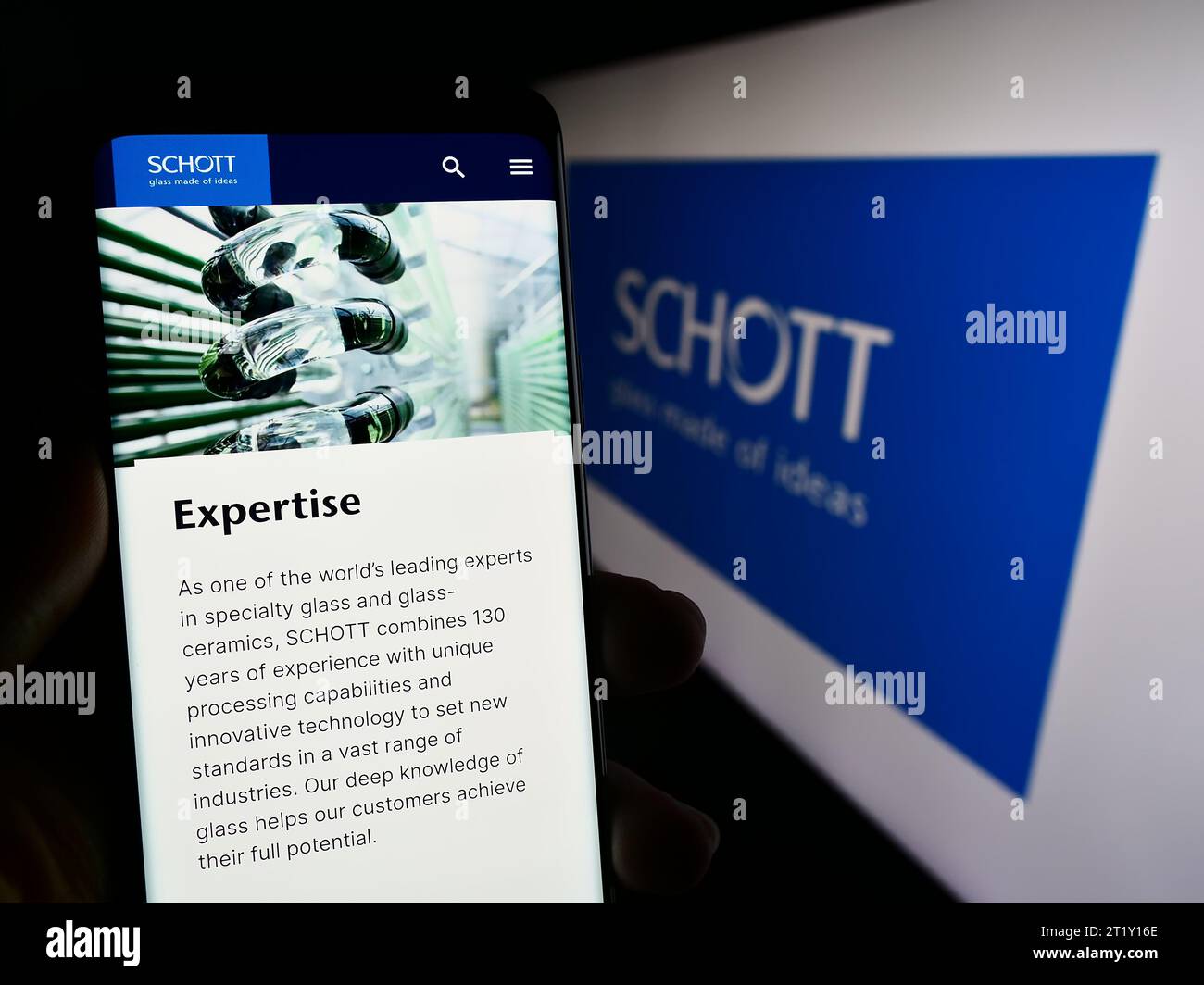 Person holding smartphone with webpage of German glass manufacturing ...
