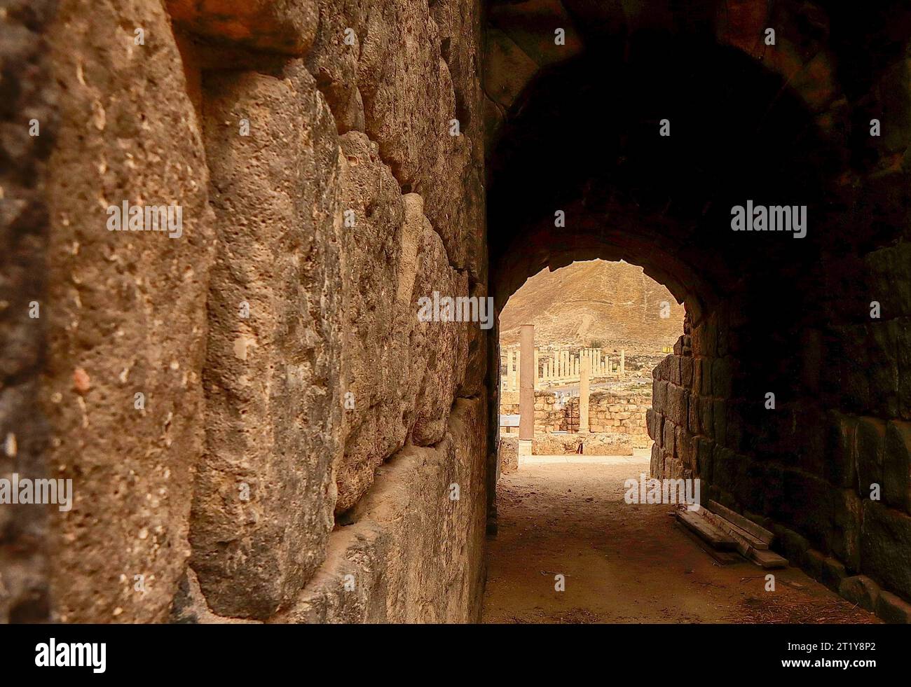 A colonnade through an arch in ancient stone walls around the city of ...