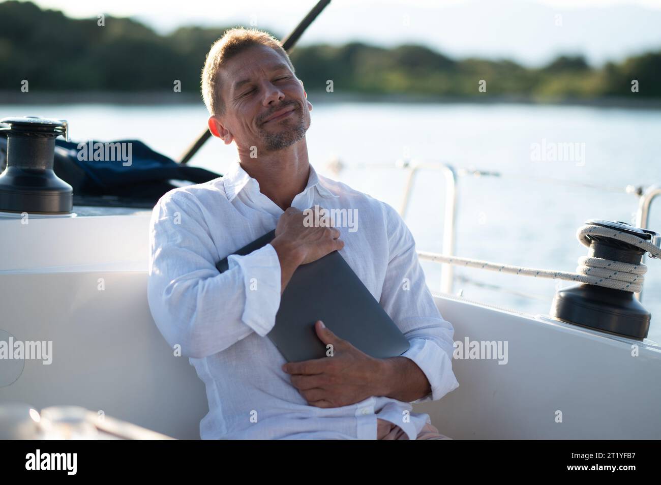 Man on a yacht deck with alaptop in hands Stock Photo - Alamy