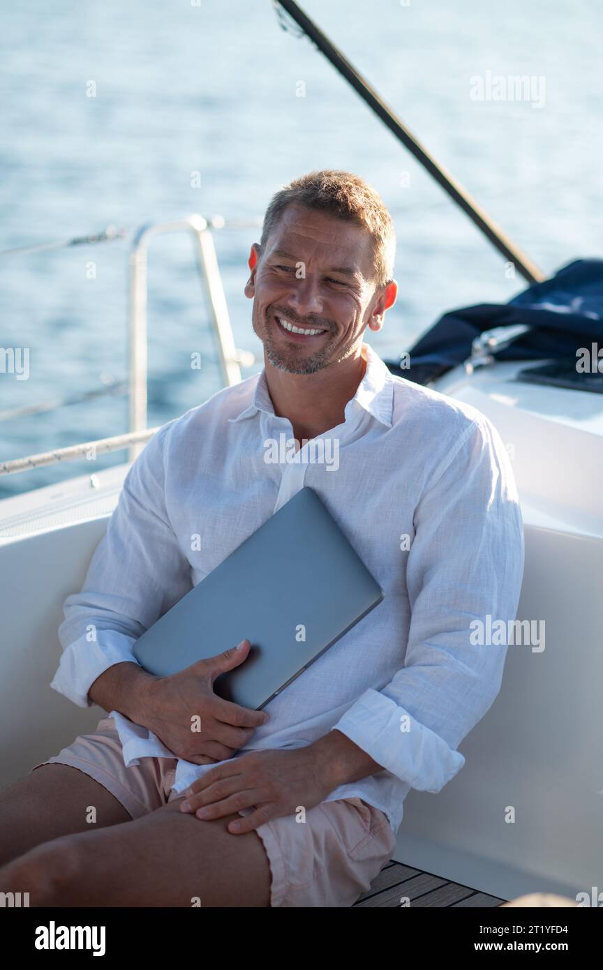 Man on a yacht deck with alaptop in hands Stock Photo - Alamy