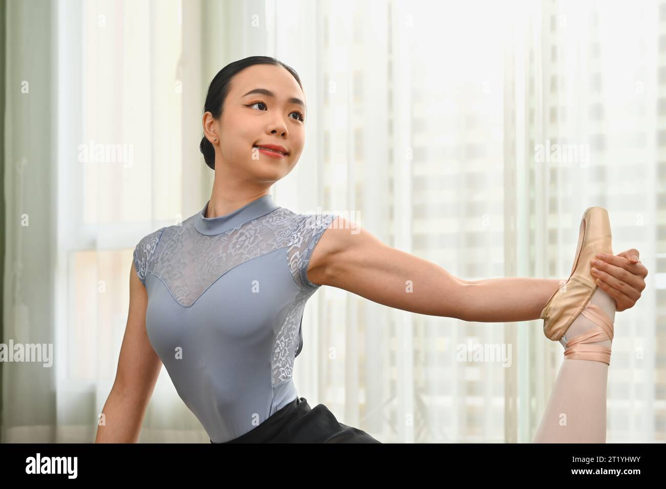 Beautiful young ballerina doing stretching exercises on the floor while ...