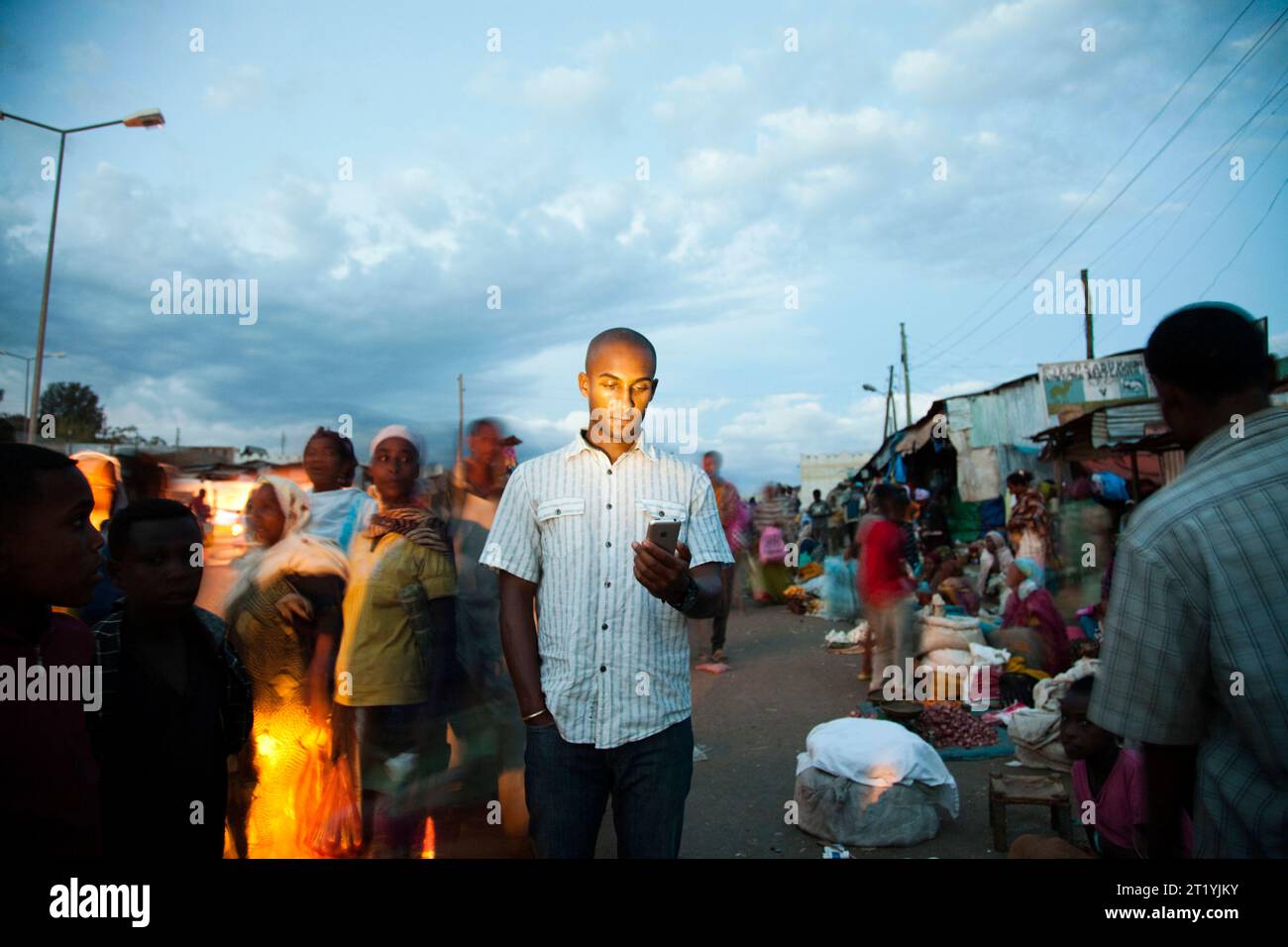 A young Ethiopian man stands in a crowded city market in an ...