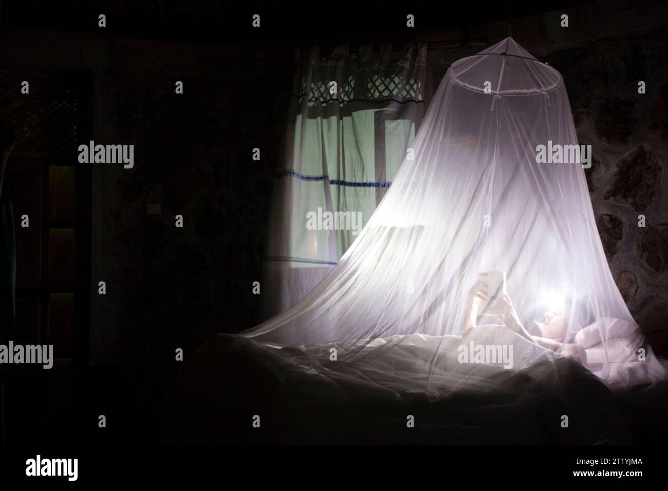 A young man sleeps inside a mosquito net at an ecolodge in Ethiopia ...