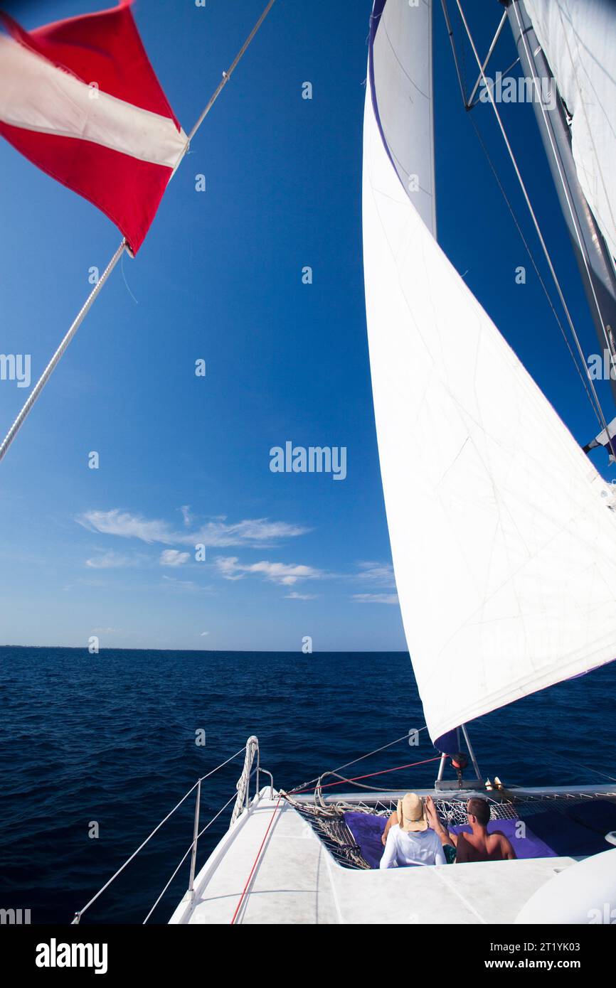 A couple sit on the front of a catamaran while enjoying a cruise on the ...