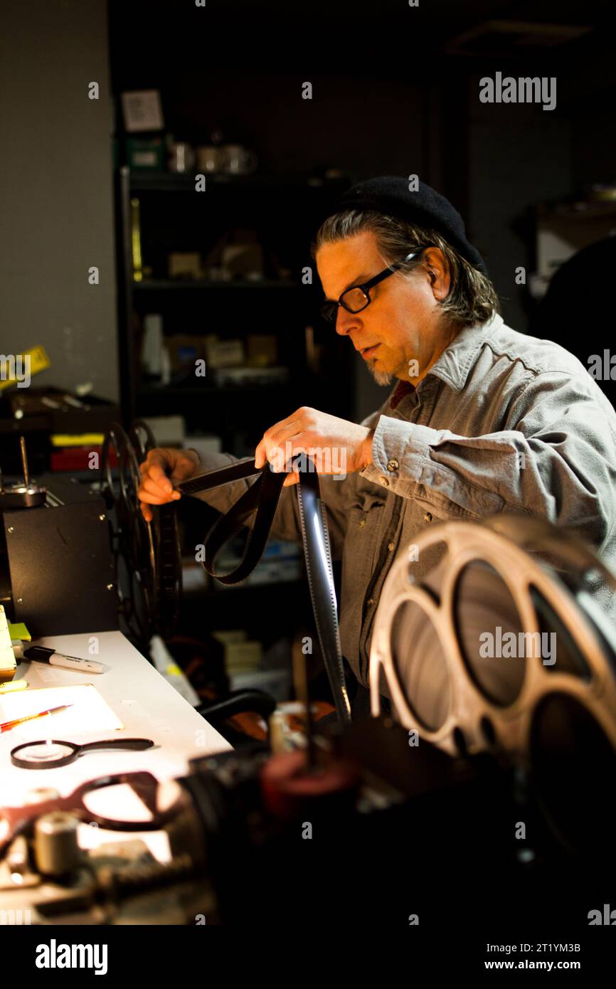 A portrait of a man who is editing vintage film in a movie theater ...