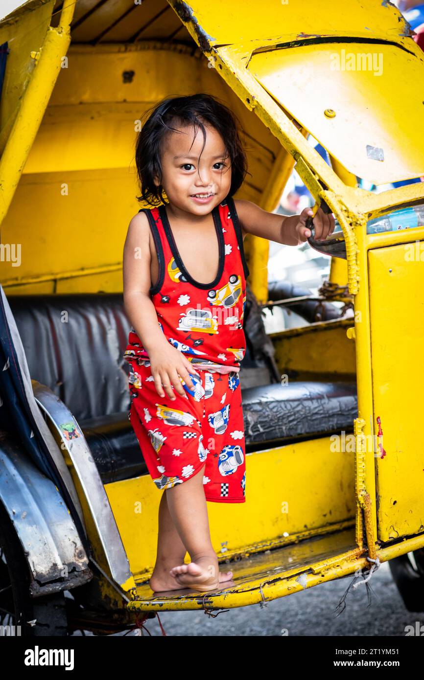 A cute Filipino girl plays on her fathers tricycle, pedicab or rickshaw ...