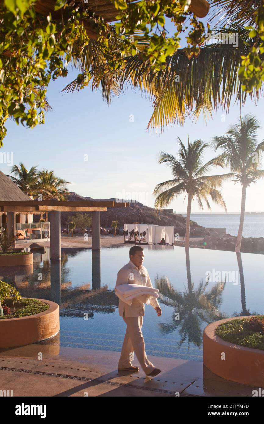 An employee carries towels next to a pool scene at a luxury hotel in La ...