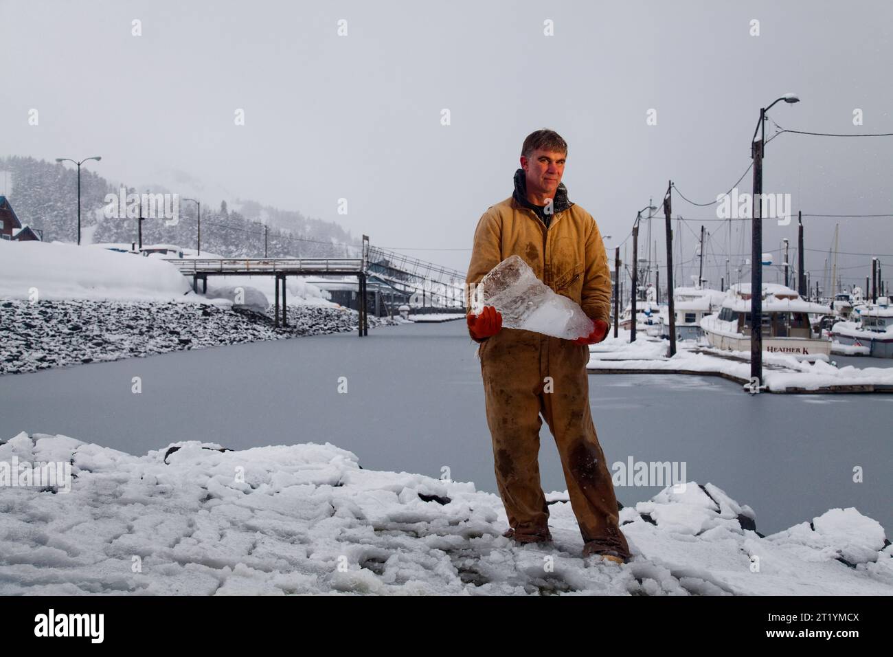 A portrait of a man holding a large ice chunk and standing near a ...