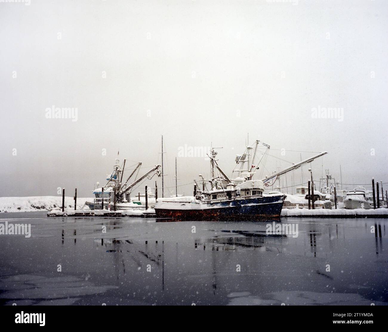 A fishing boat is moored in cold waters in a small marina in Alaska as ...