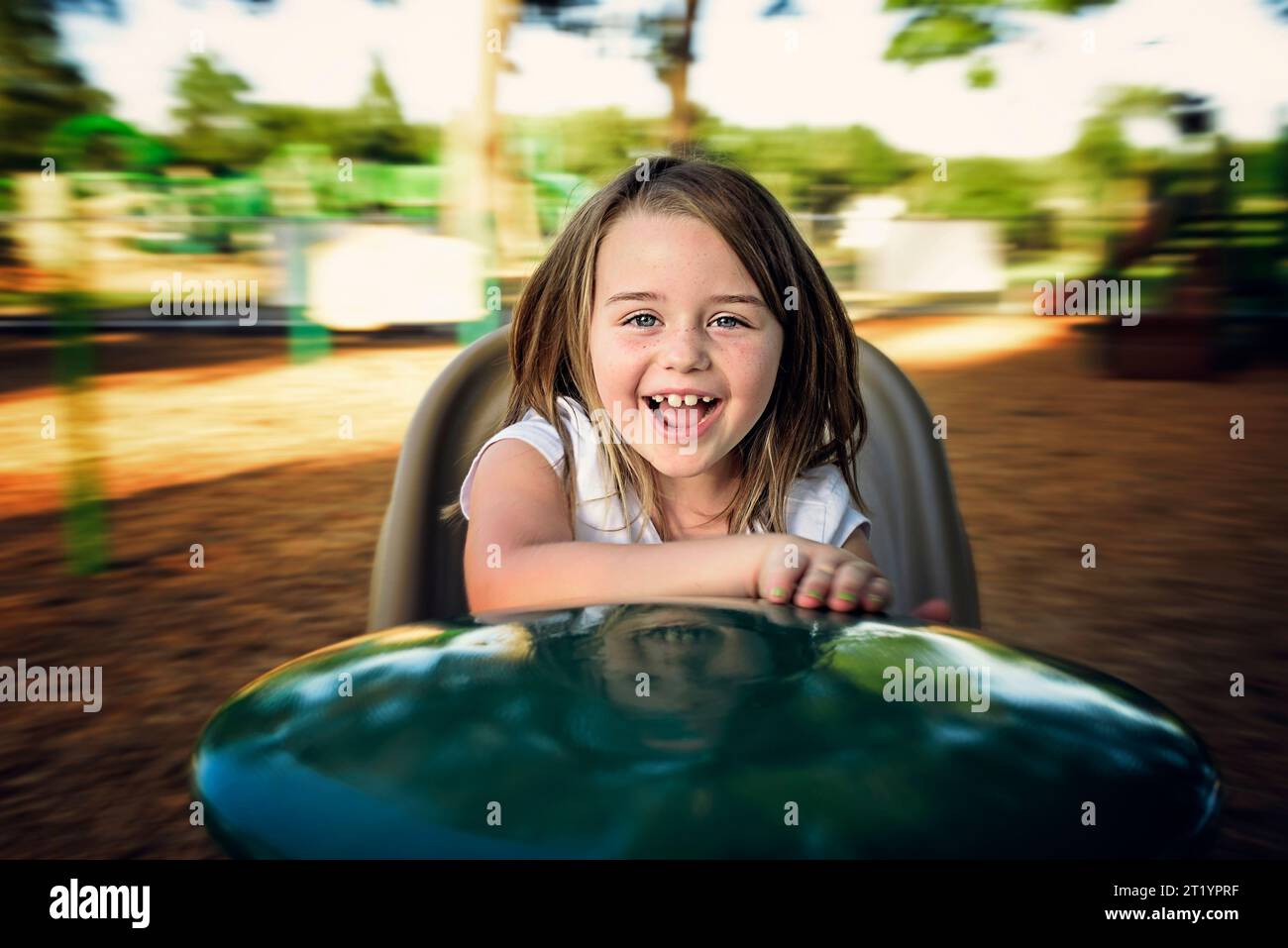 Happy little girl spinning on playground toy Stock Photo - Alamy