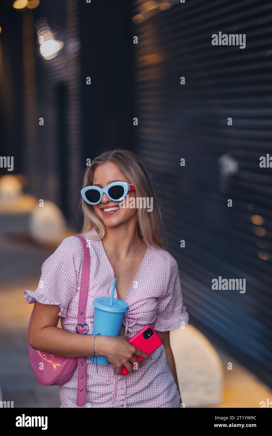 Portrait of gen Z girl in pink outfit before going the cinema to watch ...