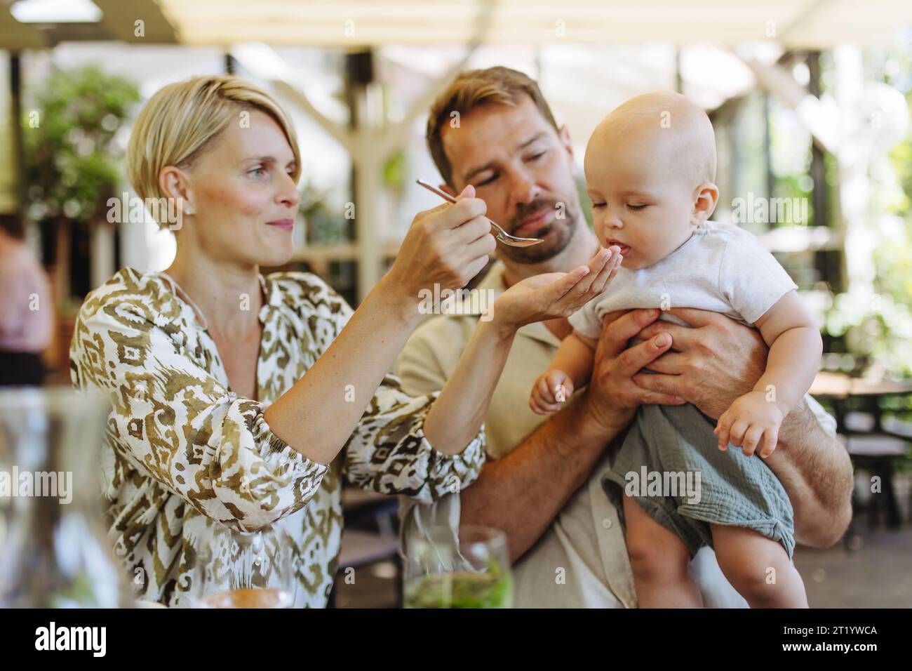 Parents in restaurant feeding small baby. Family dinner at restaurant ...