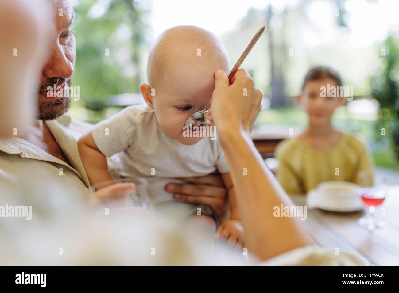 A small baby is being fed soup with big spoon. The mother feeding young ...