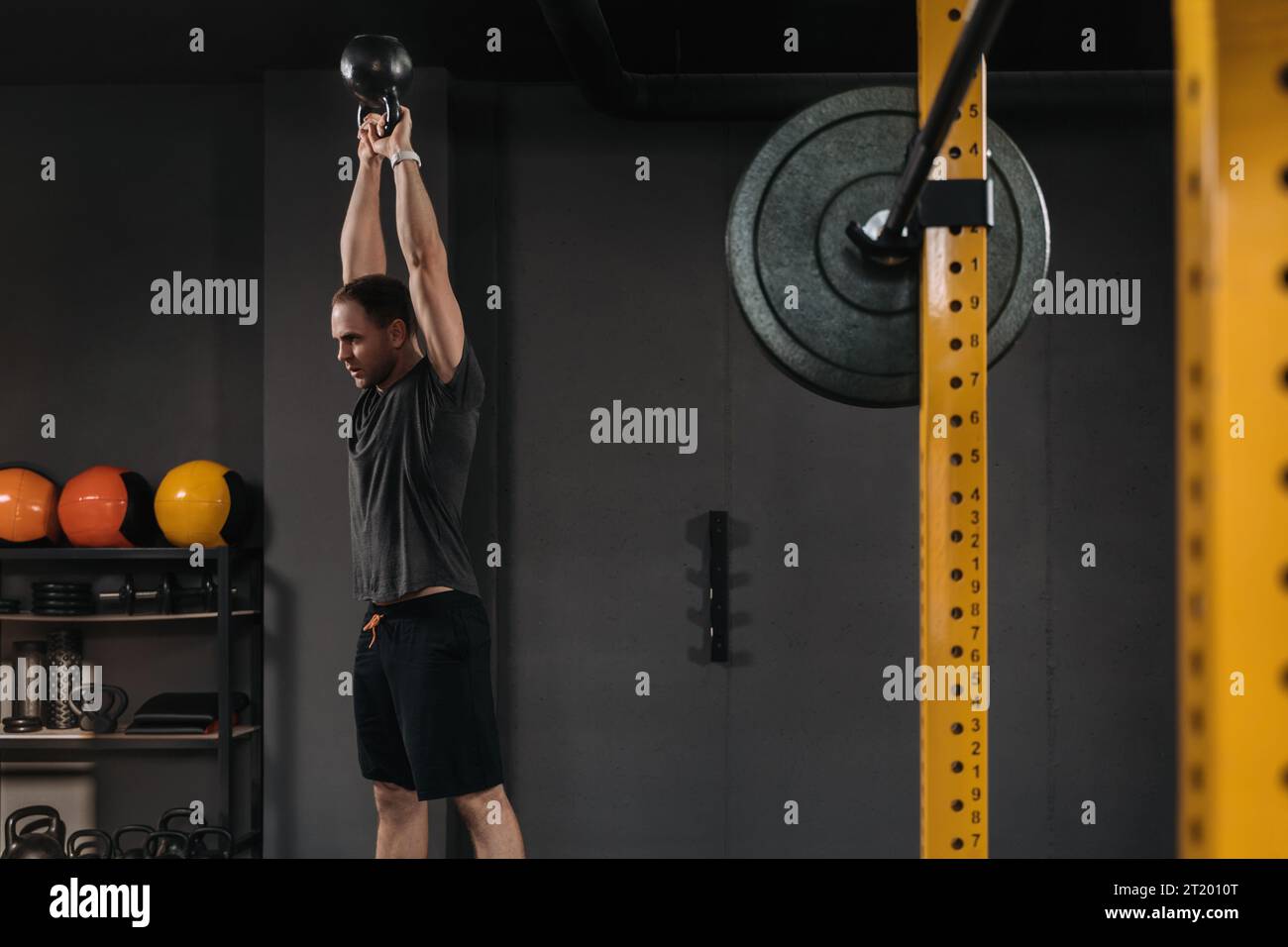 Muscular weightlifter doing an exercise with kettlebell at dark ...