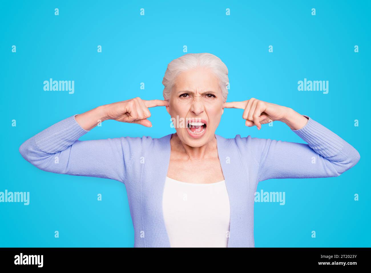 Beautiful angry gray-haired old lady wearing casual, closing her ears ...