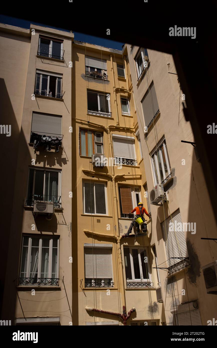 Man scaling side of apartment building to paint wall Stock Photo - Alamy