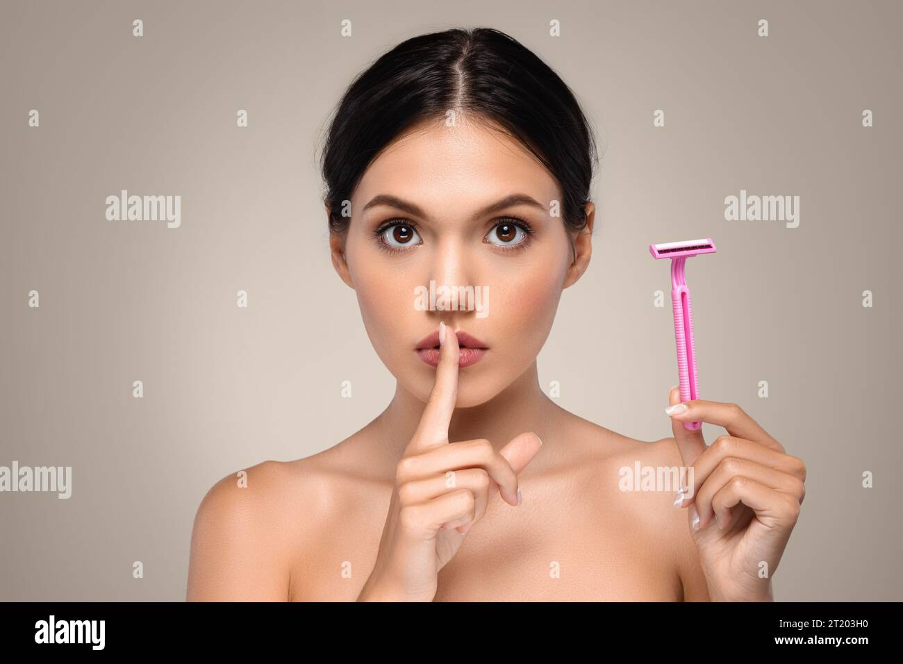 Serious calm millennial caucasian woman shows razor, puts finger to lips, makes shhh sign Stock ...