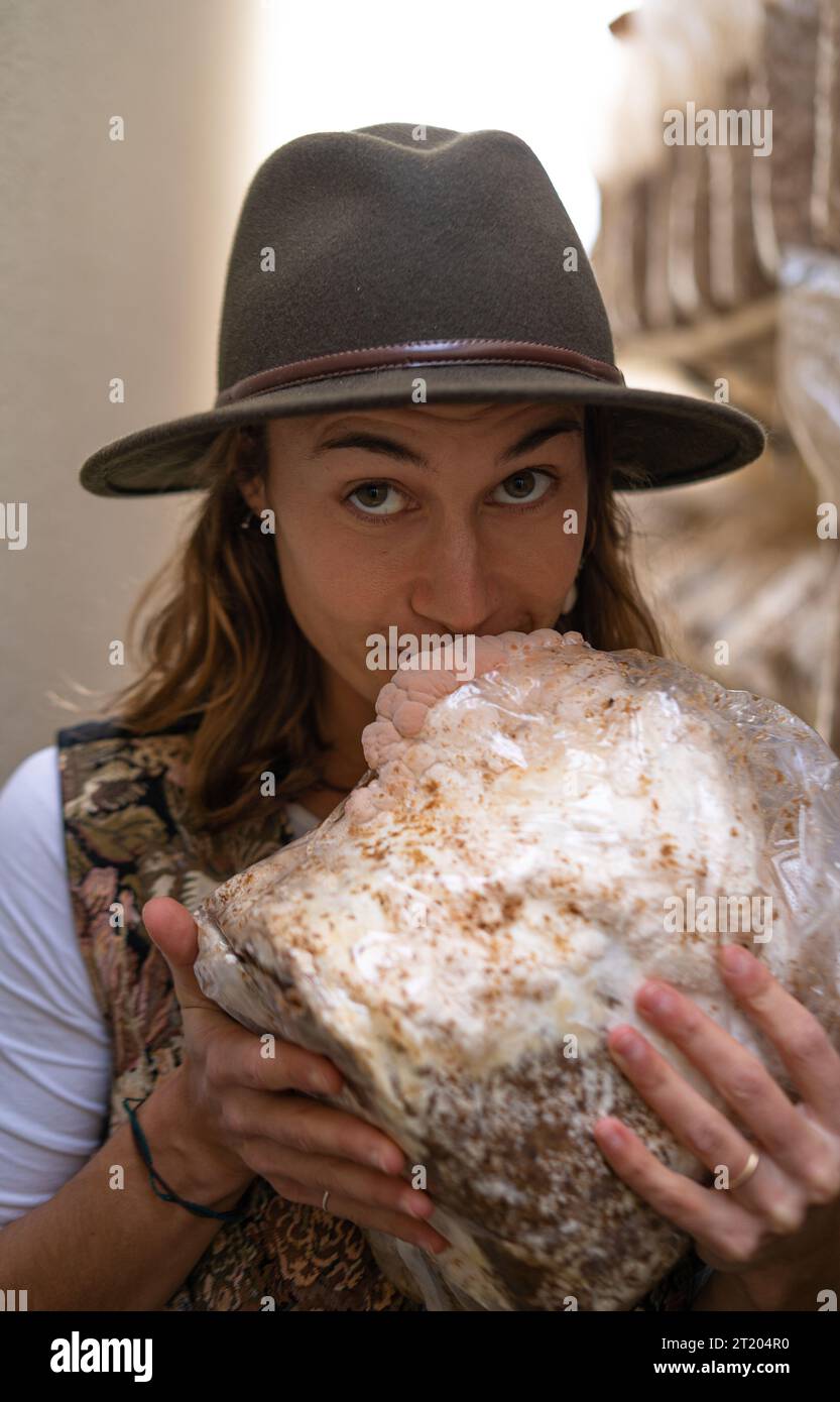 Young woman holding mycelium substrate with lion mane mushrooms and ...