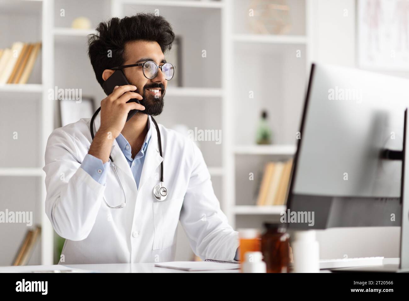 Indian Doctor Multitasking with Computer and Phone at Clinic Stock ...