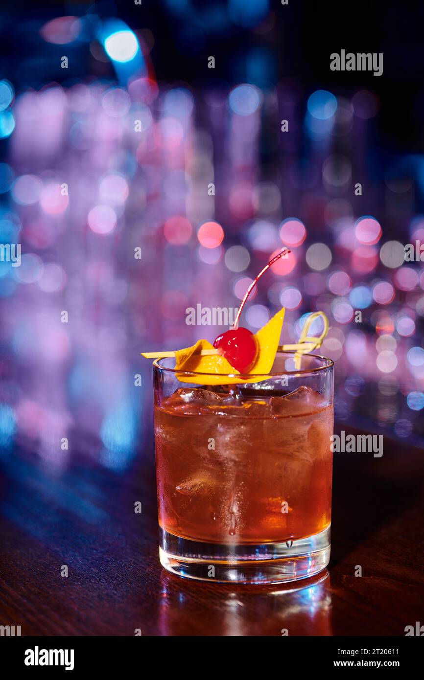 sophisticated ice cold glass of negroni garnished with cherry with bar ...