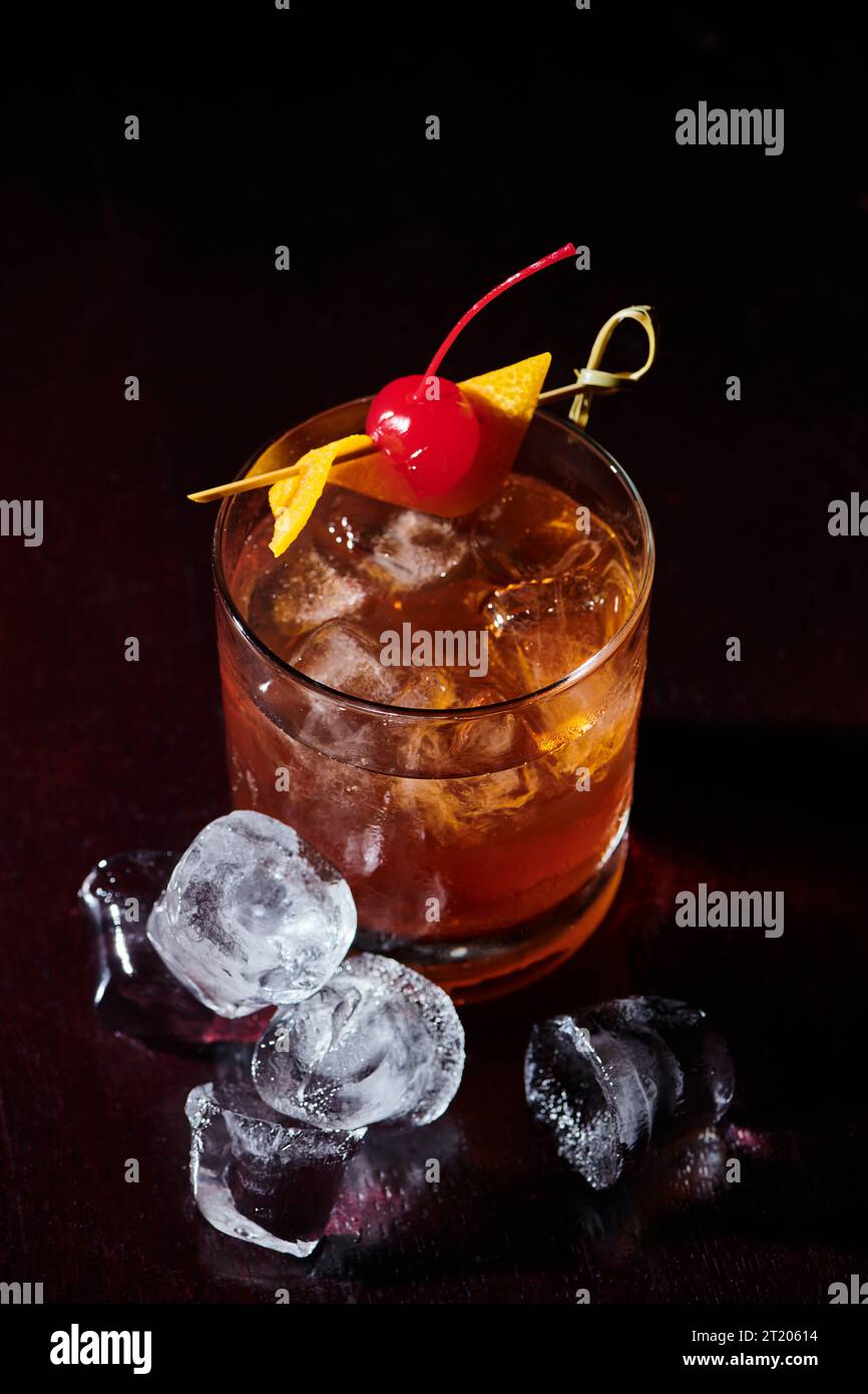 thirst quenching negroni with cocktail cherry and ice cubes on black ...