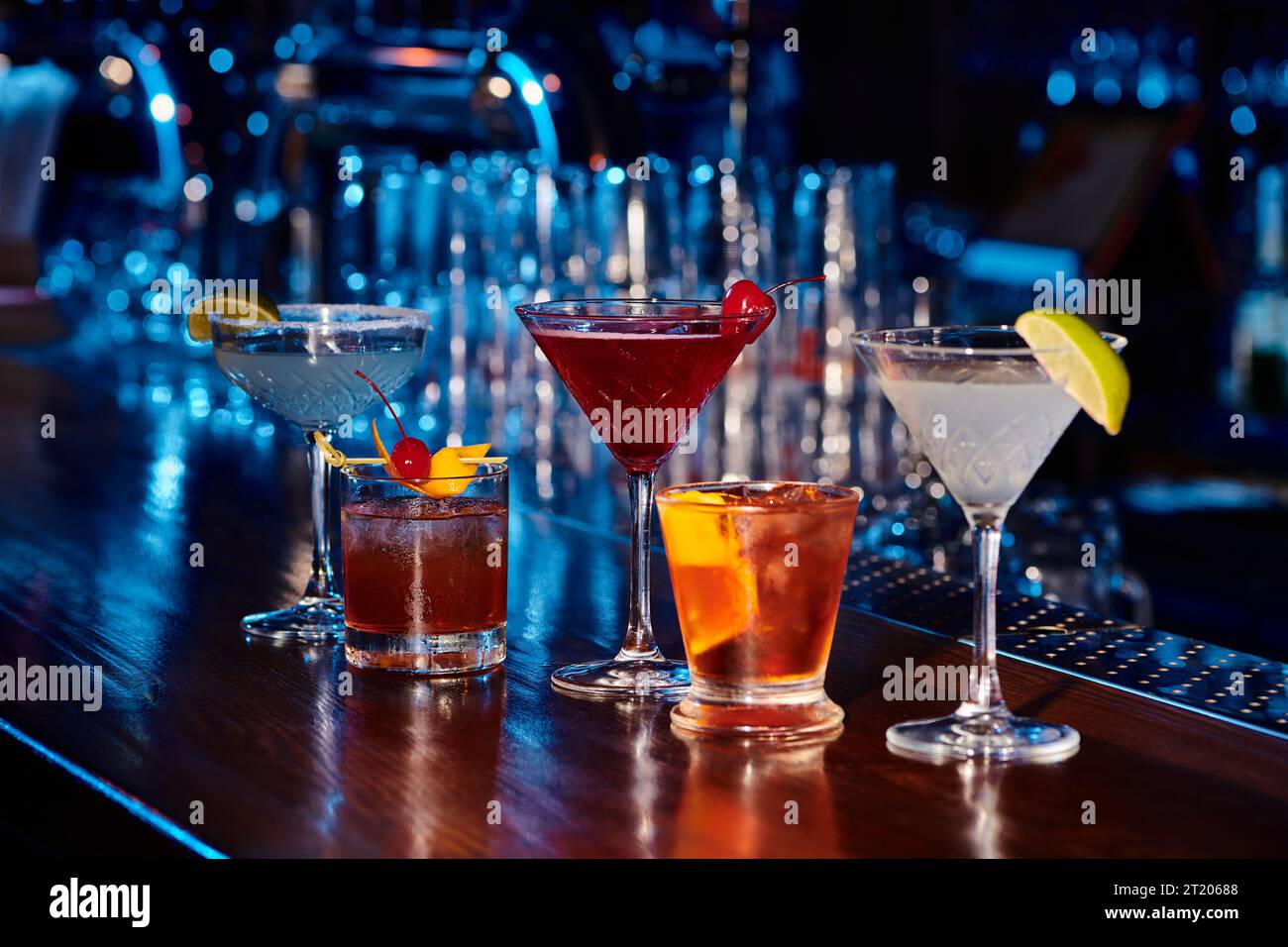 five exotic thirst quenching cocktails on bar counter with bar on ...